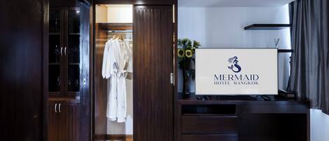 Quarto de hotel com um guarda-roupa de madeira, uma toucador com espelho e uma placa do Hotel Mermaid Bangkok.