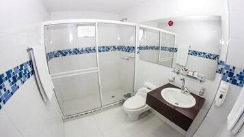 Uma casa de banho moderna com cabine de duche em vidro, sanita branca e lavatório com espelho em cima.