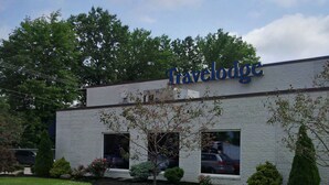 Edifício Travelodge com fachada de tijolos, grandes janelas e estacionamento em frente.