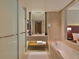 Casa de banho moderna com um espelho grande, uma banheira e uma toucador com lavatório.