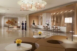 Um lobby moderno com balcão de recepção, áreas de estar e elementos decorativos.