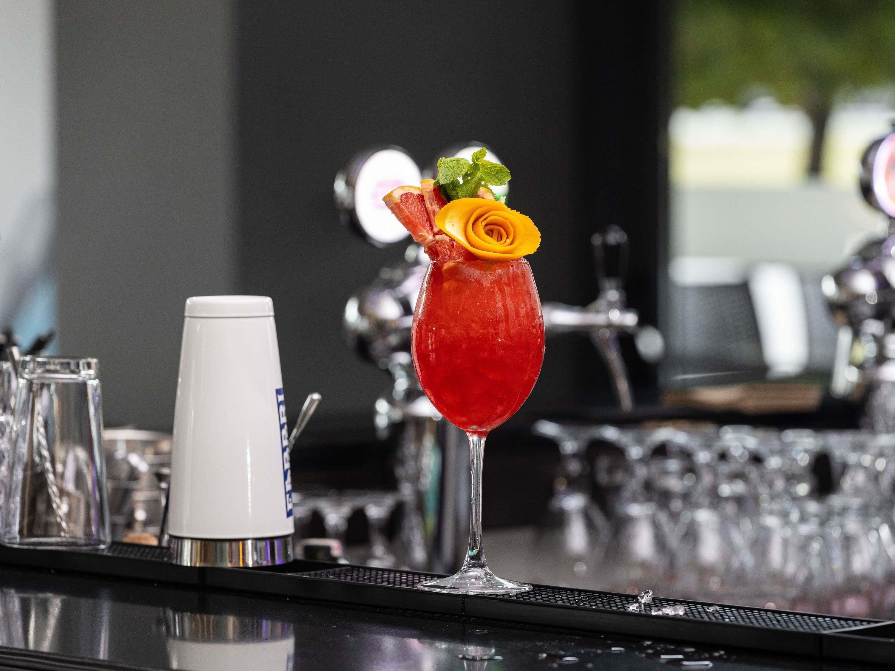 Uma área de bar com uma taça de cocktail, uma chávena branca e utensílios de bar.