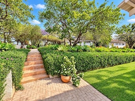 Um jardim bem cuidado com um caminho de pedras que leva a uma casa.