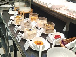 Buffet com diversos alimentos e pratos, incluindo cereais, arroz e uma tigela de sopa.