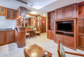 Uma sala de estar ampla com armários de madeira, uma TV de tela plana, uma mesa de centro e uma área de jantar com mesa e cadeiras.