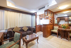 Uma sala de estar ampla com um sofá de couro marrom, uma mesa de centro de madeira e uma área de jantar com mesa e cadeiras de madeira.