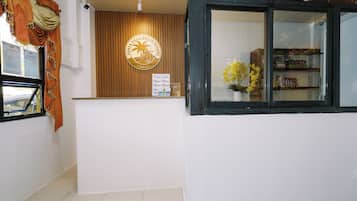 Balcão de recepção com parede de painéis de madeira, um logotipo e uma janela com vista para o interior.