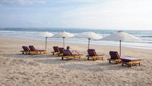 Uma praia com espreguiçadeiras e guarda-sóis.