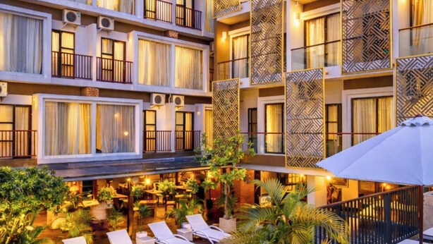 Um hotel com vários andares, área de estar ao ar livre e piscina.