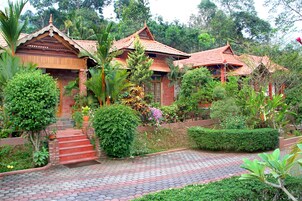 Uma casa de madeira tradicional com telhado de cerâmica, rodeada por vegetaç ão exuberante e um caminho pavimentado.