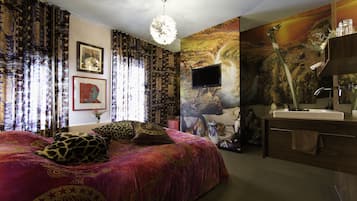 Quarto com cama grande, TV de tela plana na parede e banheiro com pia e espelho.