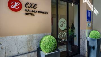 Exterior do Hotel Exe Málaga Museos com design moderno, incluindo logotipo, nome e entrada de vidro.