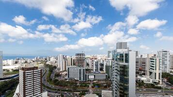 Paisagem urbana com edifícios modernos altos, céu claro e vista do oceano.