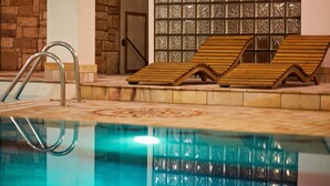 Piscina com espreguiçadeiras e escada de metal.