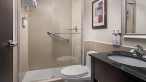 Um banheiro moderno com box de vidro, vaso sanitário branco e pia escura com espelho.