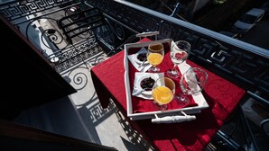 Uma mesa de jantar com uma bandeja de comida e bebidas numa varanda.