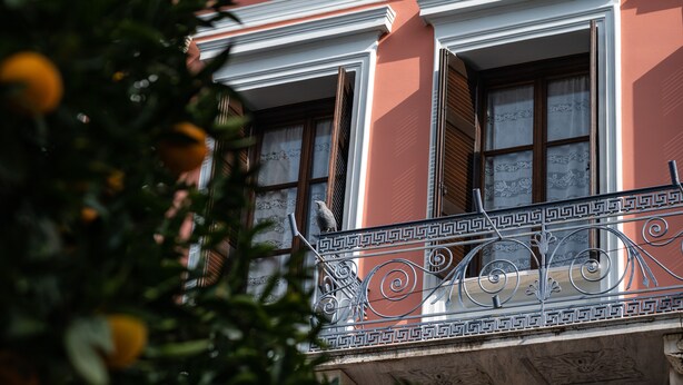 Um edifício com varanda, detalhes em grades de metal ornamentadas e janela com persianas.