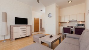 Uma sala de estar moderna com televisão de tela plana, sofá, mesa de centro e um espaço de refeições com micro-ondas.