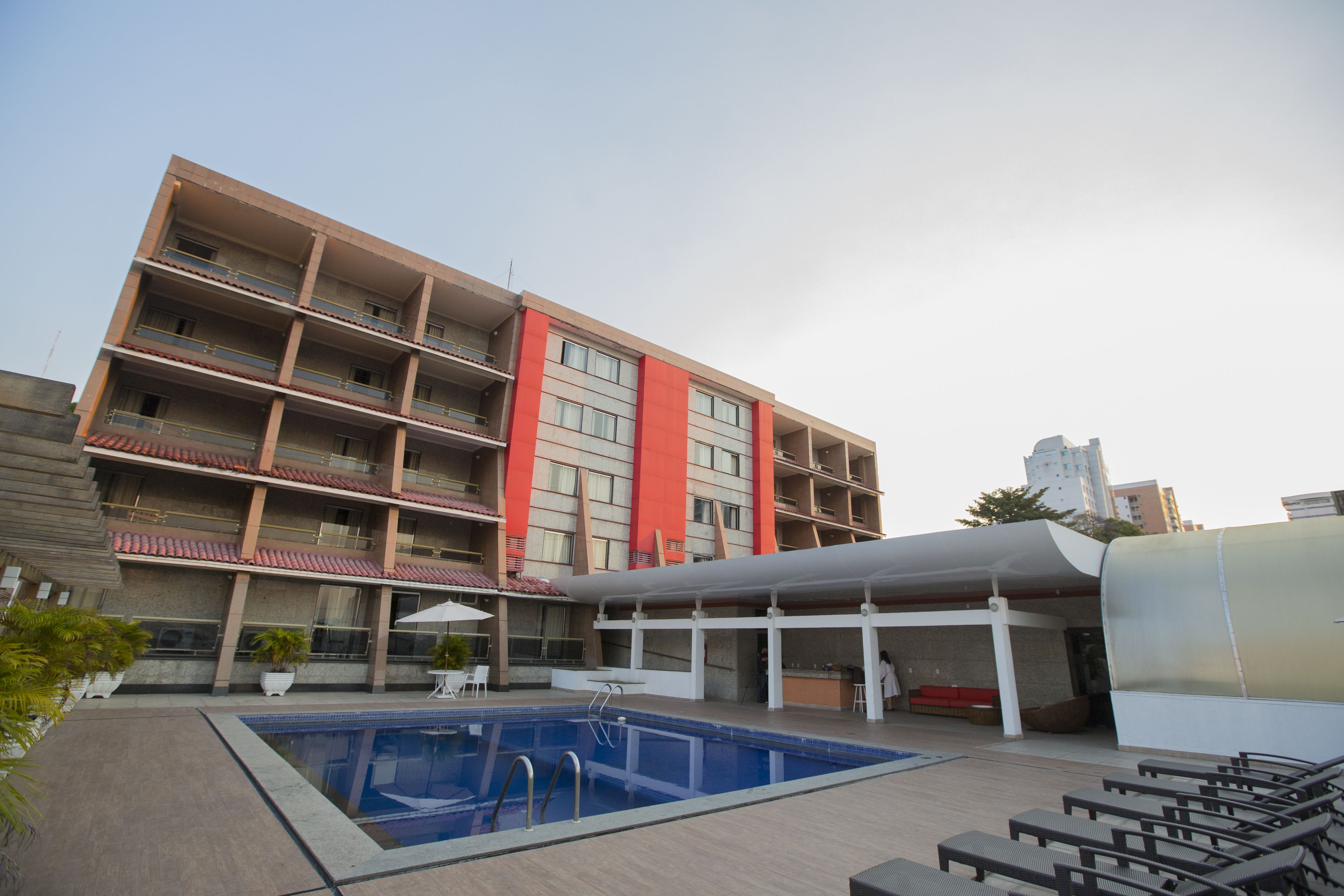 Um hotel com piscina, área de estar externa e espaço coberto.