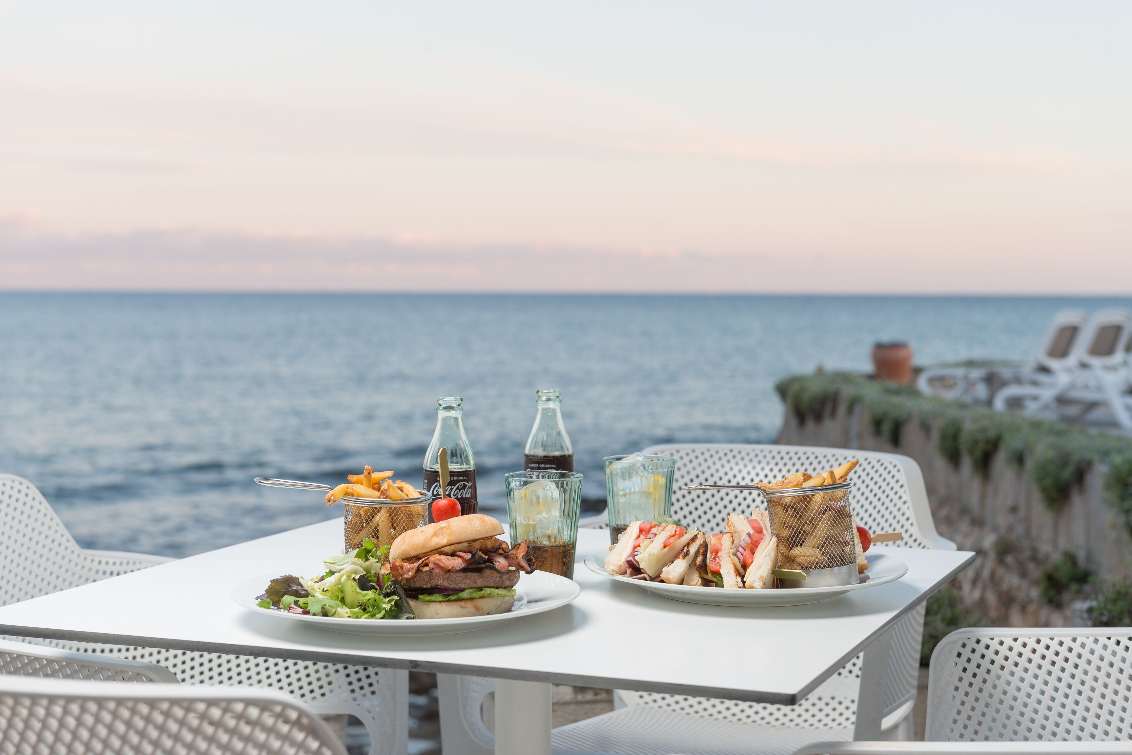 Mesa posta com comida e bebidas à beira-mar, com vista para o oceano.