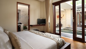 Quarto de hotel com uma cama grande, televisão, escrivaninha e vista para a piscina e área externa.