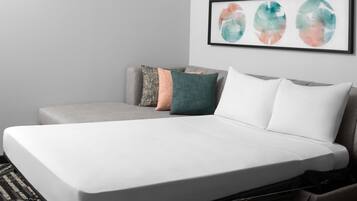 Quarto moderno com cama, sofá cinza e pintura abstrata emoldurada na parede.