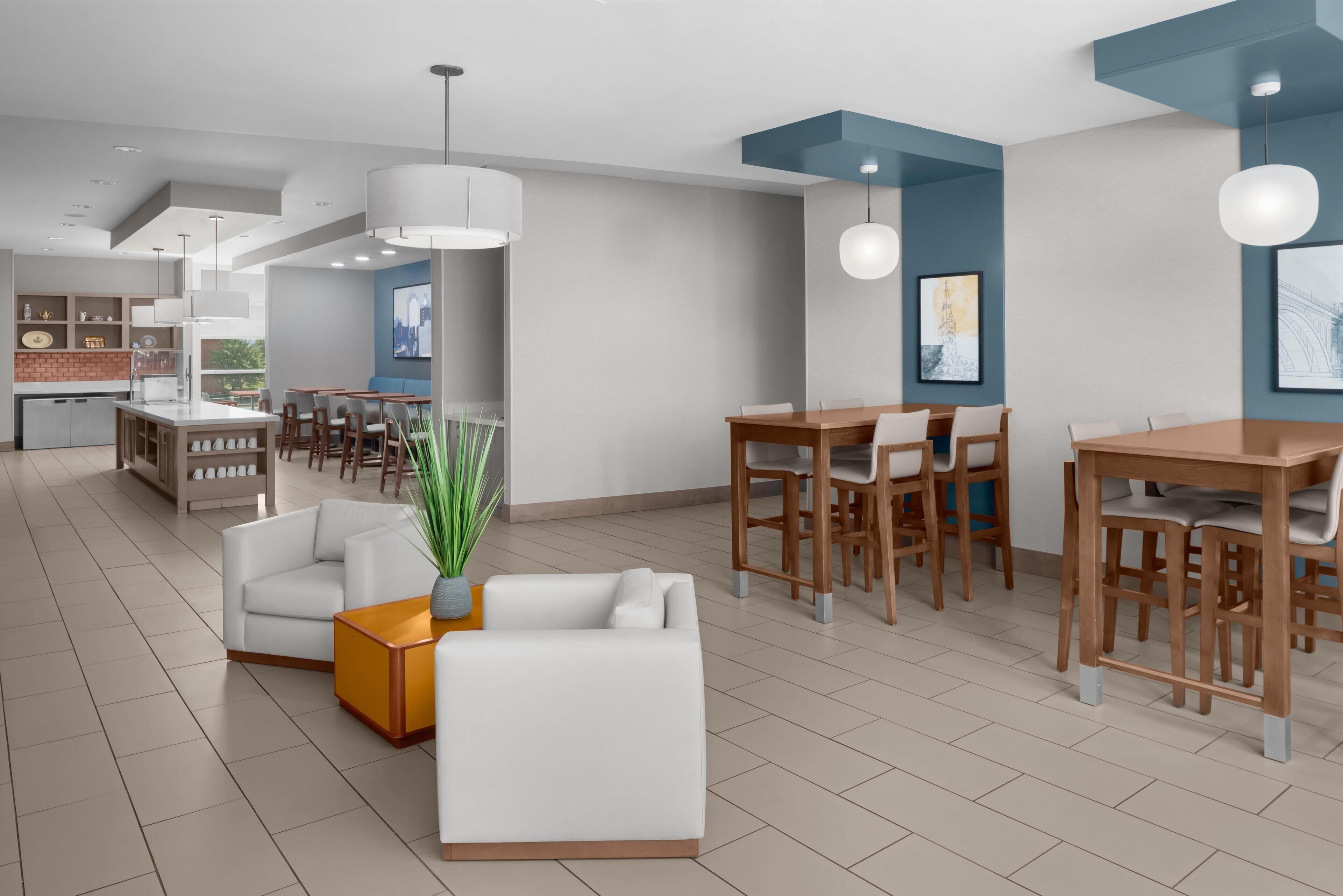 Uma sala de estar moderna com um sofá branco, mesa de centro de madeira e área de jantar com cadeiras e mesa de madeira.