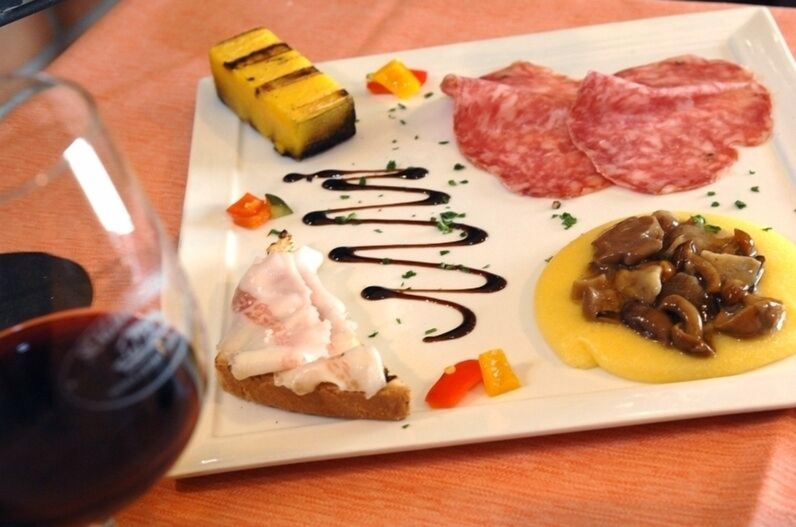 Um prato quadrado com diversos alimentos, incluindo queijo grelhado, fatias de carne, cogumelos e uma porção de creme.