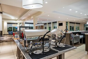 Buffet montado com churrasqueira de serviço por si, utensílios de servir e dosadores de acompanhamentos.