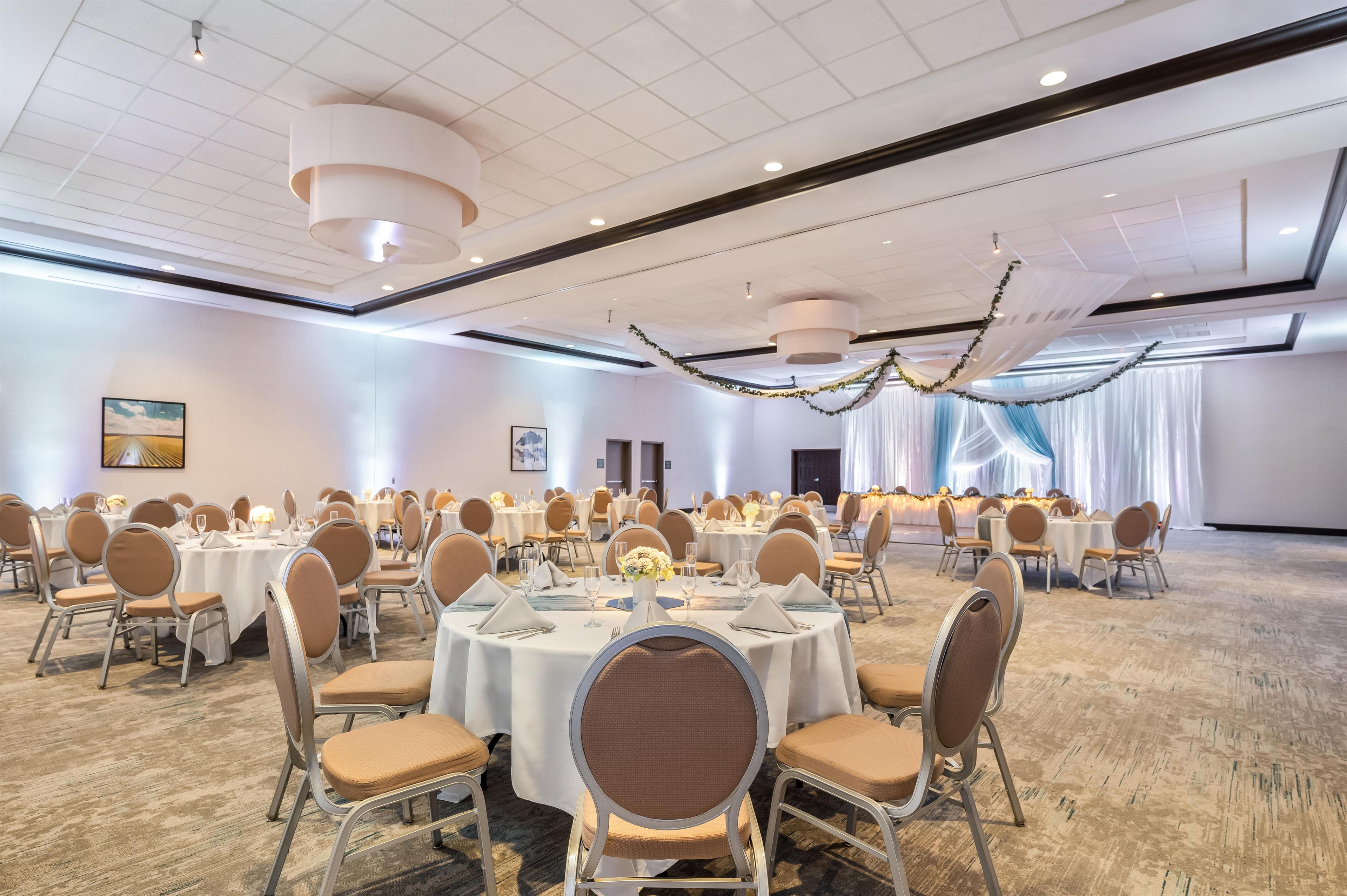 Sala de conferências com mesas redondas, cadeiras e um lustre.