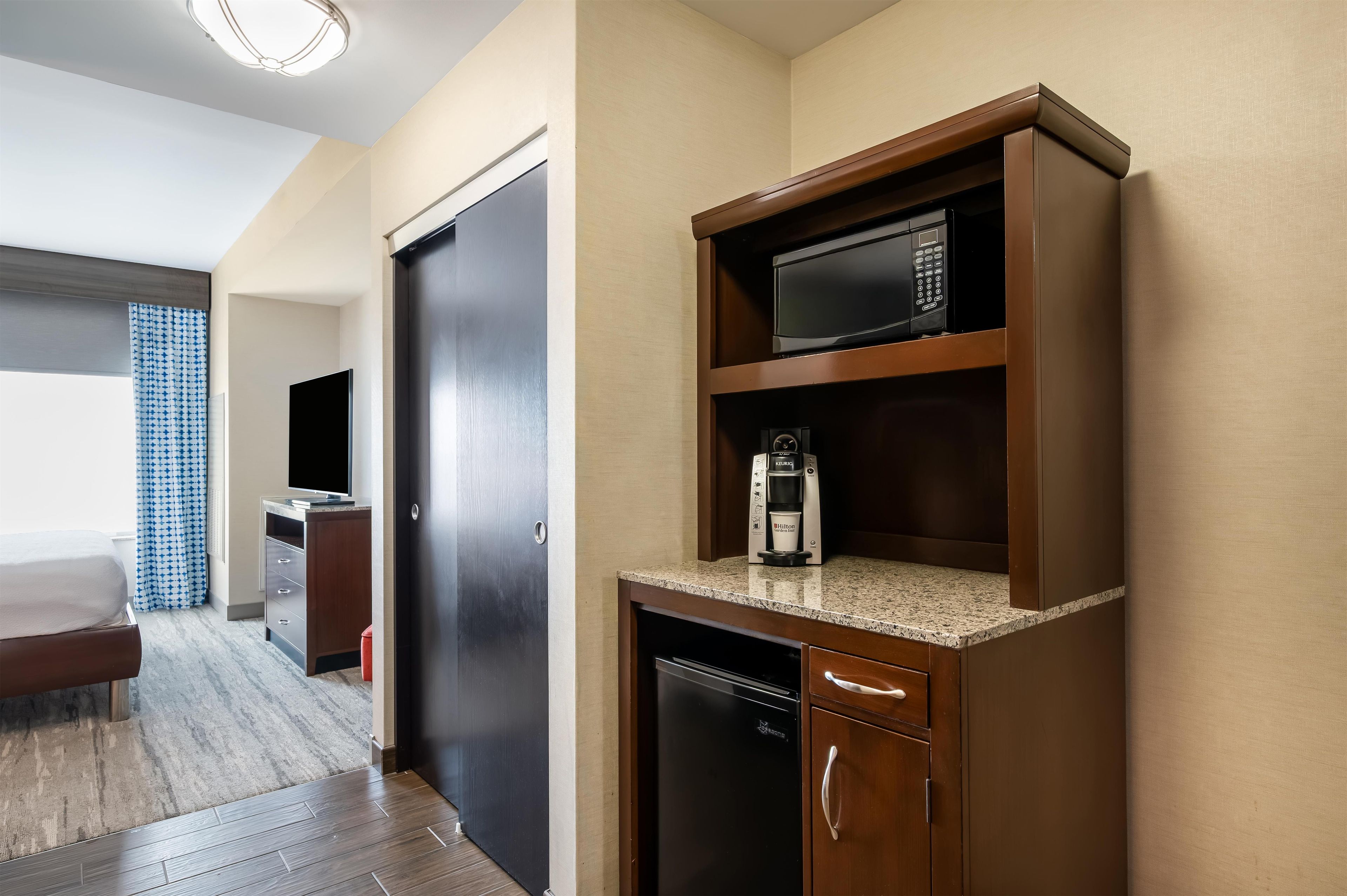 Quarto de hotel com cozinha compacta, incluindo micro-ondas, cafeteira e lava-louça.