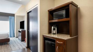 Quarto de hotel com cozinha compacta, incluindo micro-ondas, cafeteira e lava-louça.