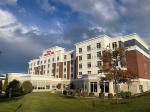 Um hotel grande, com vários andares, e uma placa de destaque com o nome Garden Inn. Apresenta uma fachada simétrica com janelas igualmente espaçadas e uma entrada central.