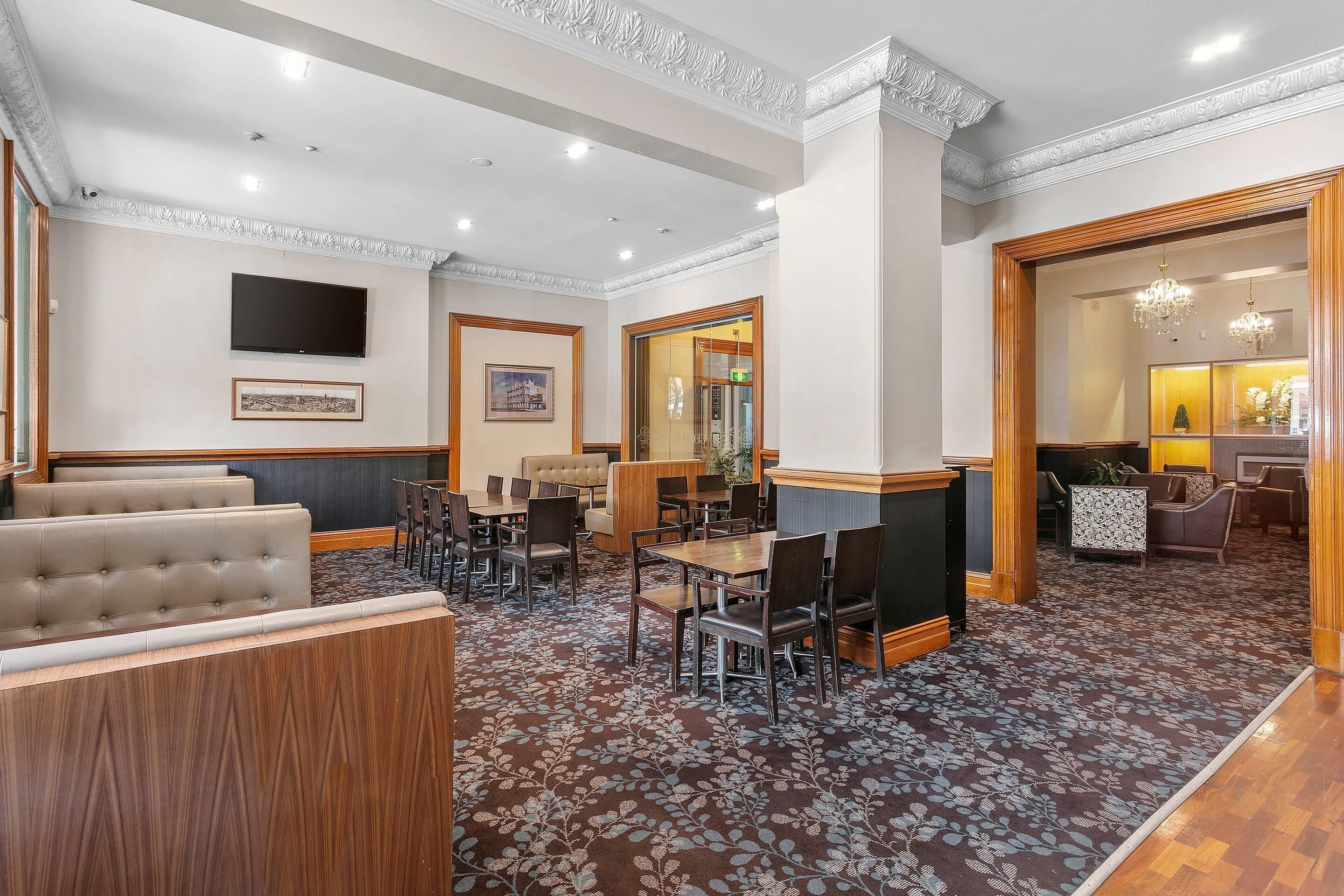 Um saguão de hotel com área de estar, balcão de recepção e uma tela grande.