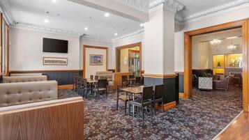 Um saguão de hotel com área de estar, balcão de recepção e uma tela grande.