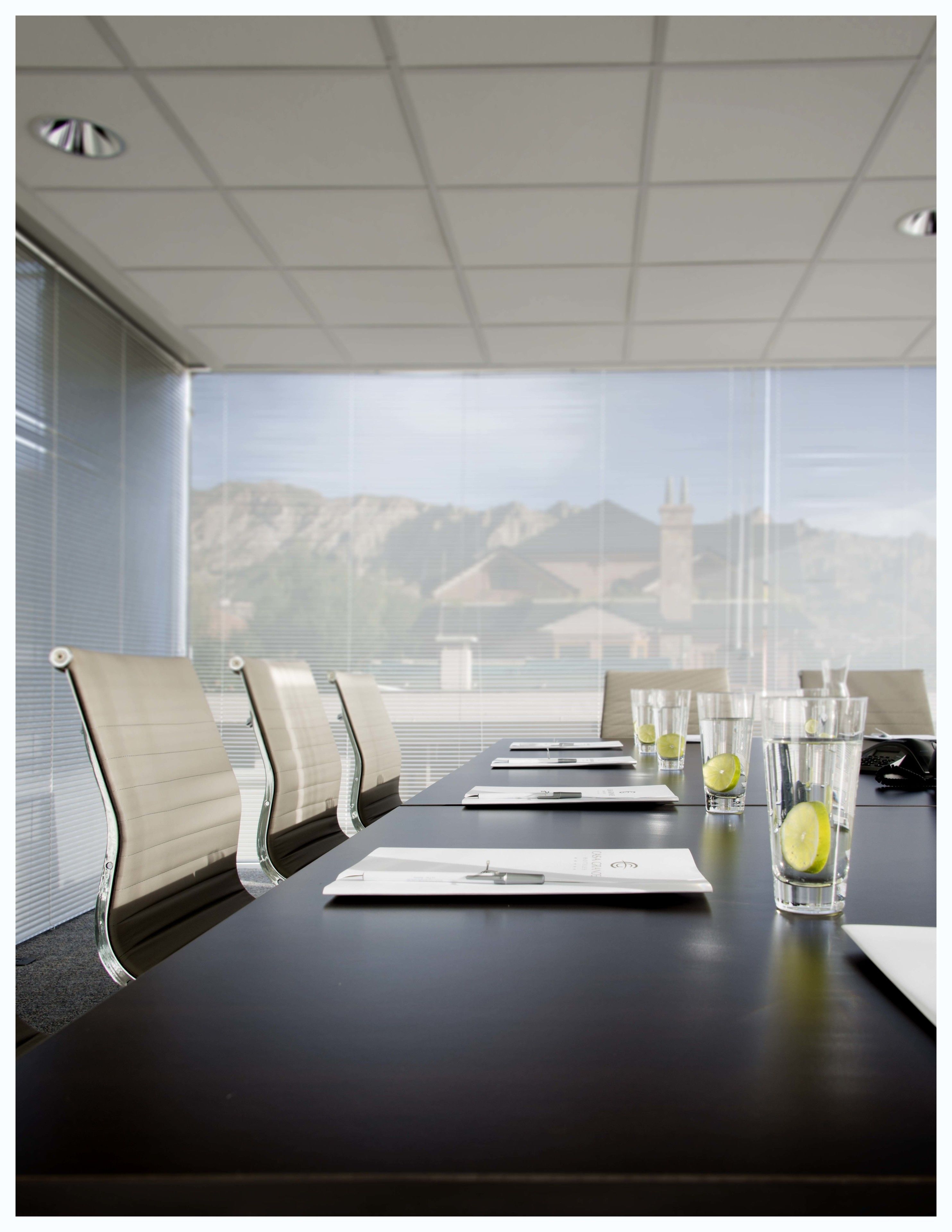 Sala de conferência com uma mesa comprida, cadeiras e copos de água com rodelas de limão.