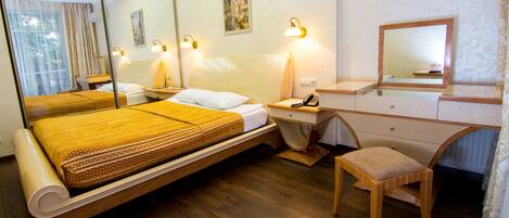 Quarto de hotel com cama, escrivaninha, cadeira, cômoda e espelho.