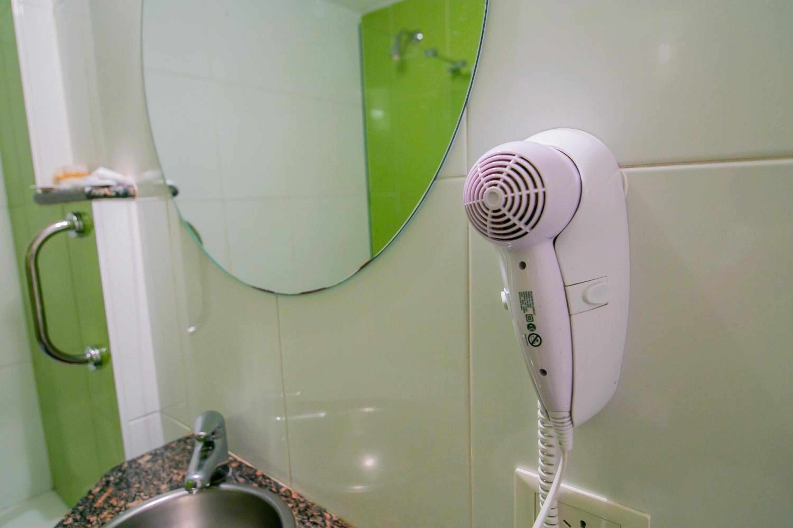 Casa de banho com secador de cabelo fixado na parede, uma pia com bancada de granito e um espelho.