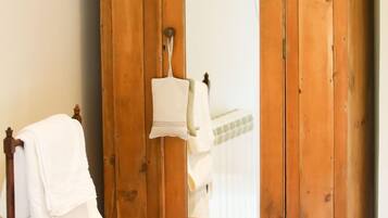 Um guarda-roupa de madeira com espelho, um porta-toalhas e um aparelho eletrônico branco no chão.