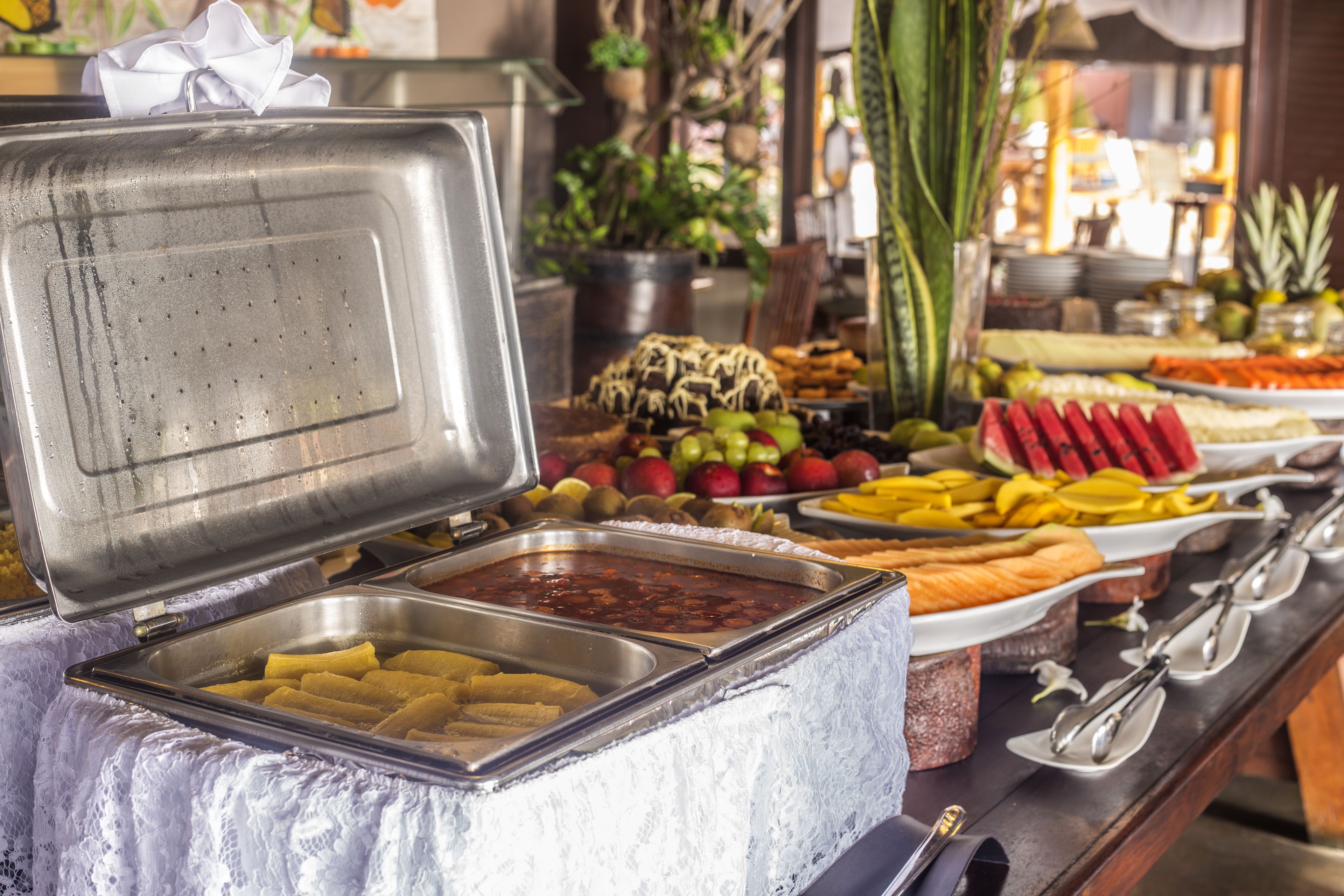 Buffet com diversas opções de comida, incluindo frutas, doces e uma estação de bebidas quentes.