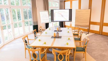 Uma sala de conferências com uma mesa comprida, cadeiras, um telão e um quadro branco.