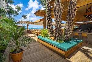 Um deck ao ar livre com piso de madeira, áreas de estar e um bar.