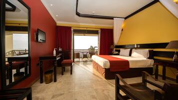 Quarto de hotel com cama, escrivaninha, cadeira e televisão.