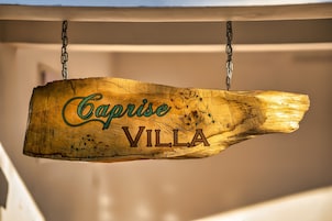 Uma placa de madeira com o texto 'Caprise VILLA' pendurado numa corrente.