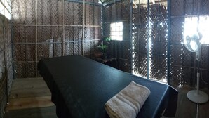 Um quarto com uma cama, uma mesinha com uma planta e um ventilador.