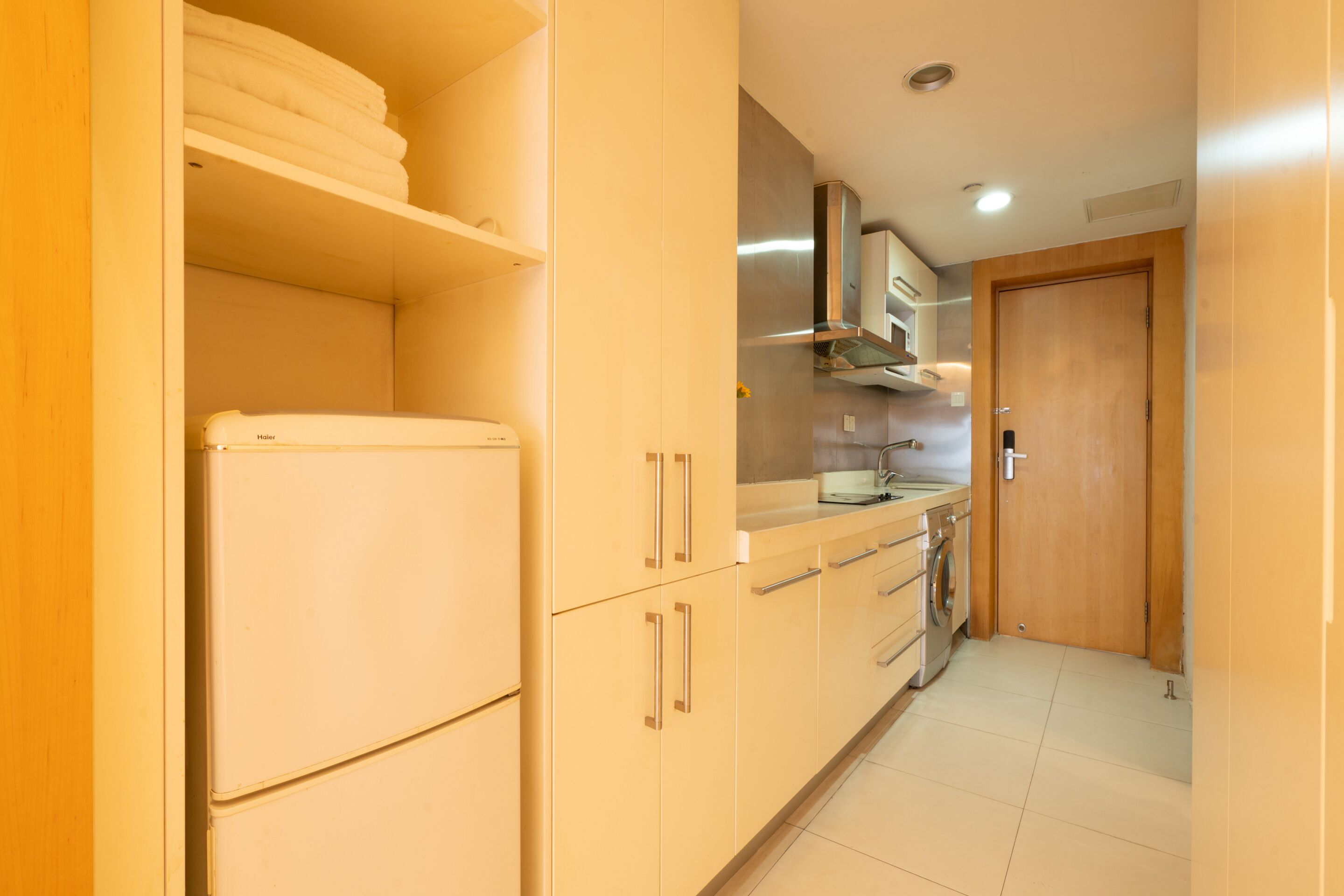Uma cozinha compacta com geladeira, forno e máquina de lavar.