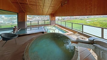 Interior em madeira com banheira de hidromassagem e vista para a cidade.