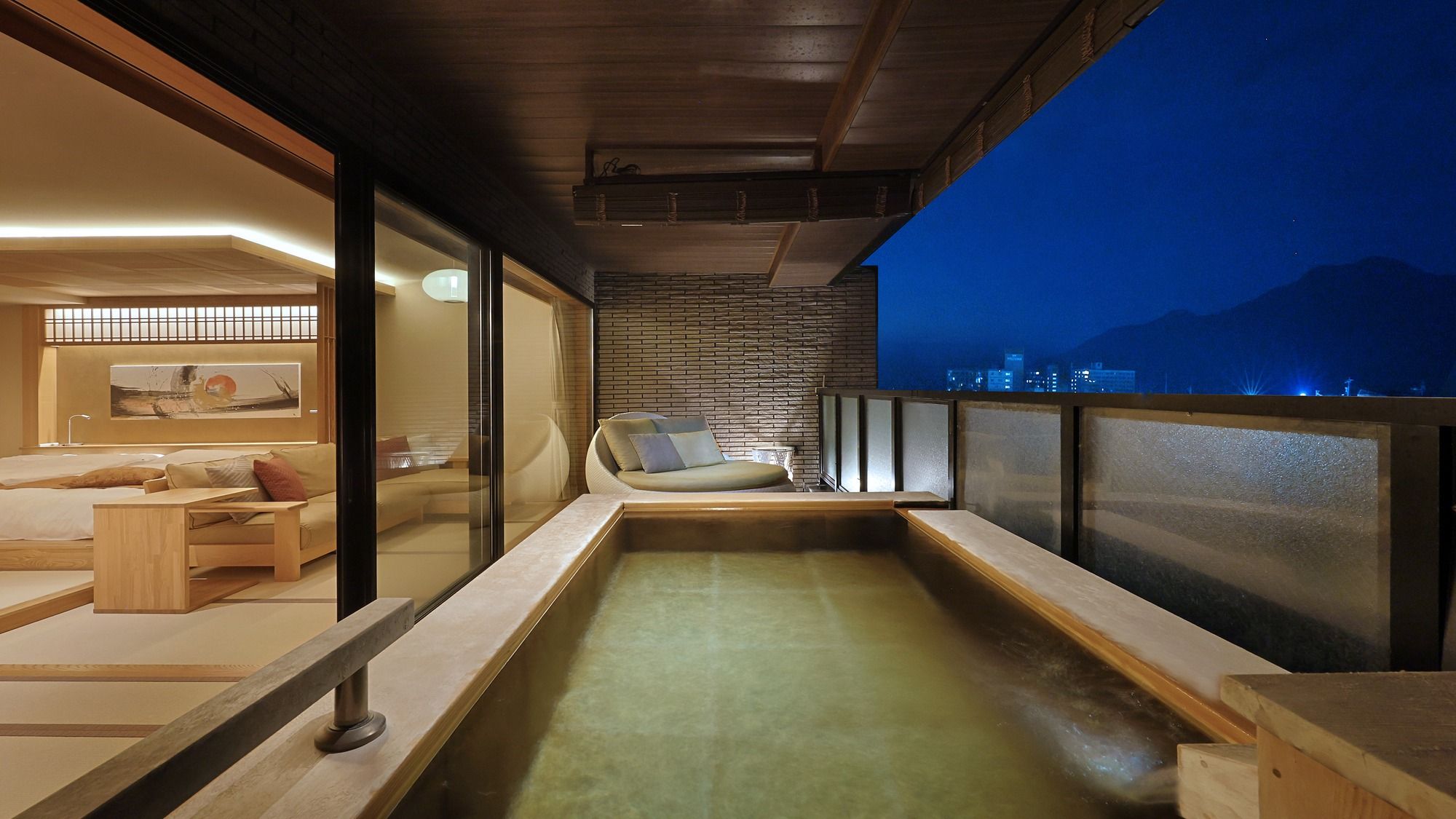 Decoração moderna com área de estar, uma piscina pequena e vista para a cidade à noite.