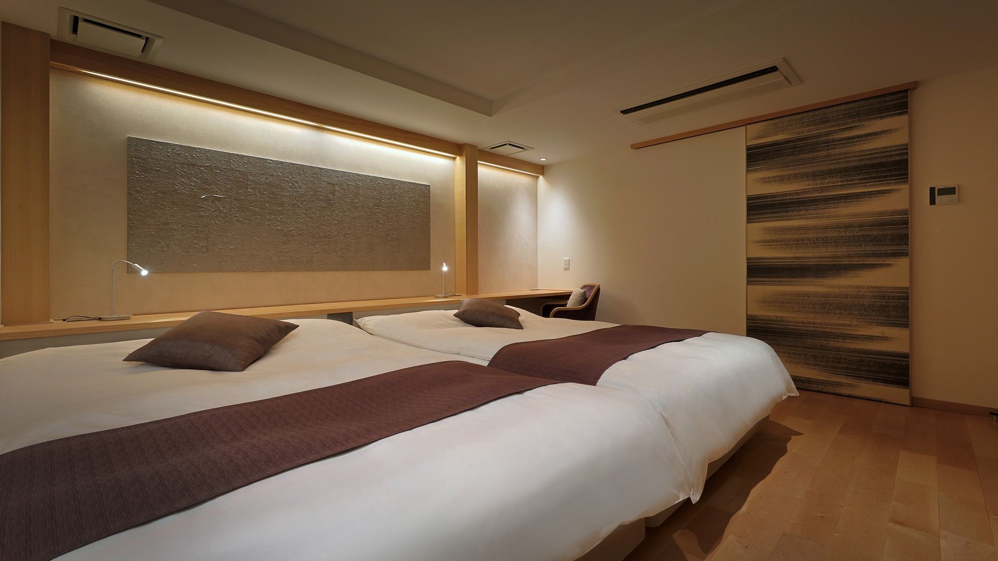 Quarto de hotel com duas camas, uma janela grande e uma parede com textura.