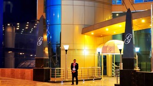 Um hotel moderno com fachada de vidro curva, entrada bem iluminada e um homem em frente.